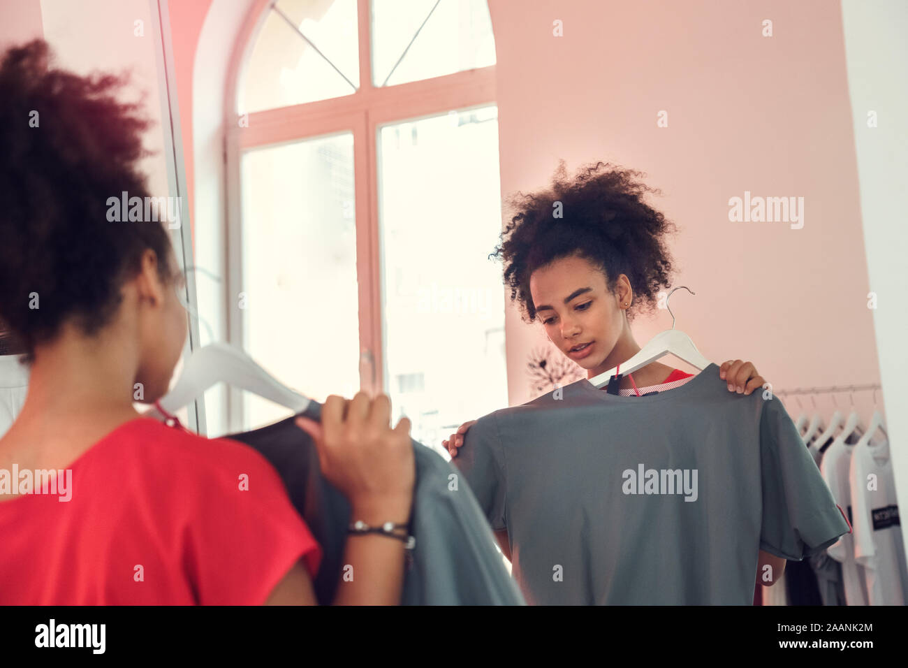 Choosing Clothes. African teenager girl standing choosing clothes from ...
