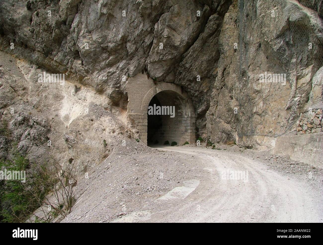 A small tunnel dug into the rock on a dirt road in the Alps. What ...