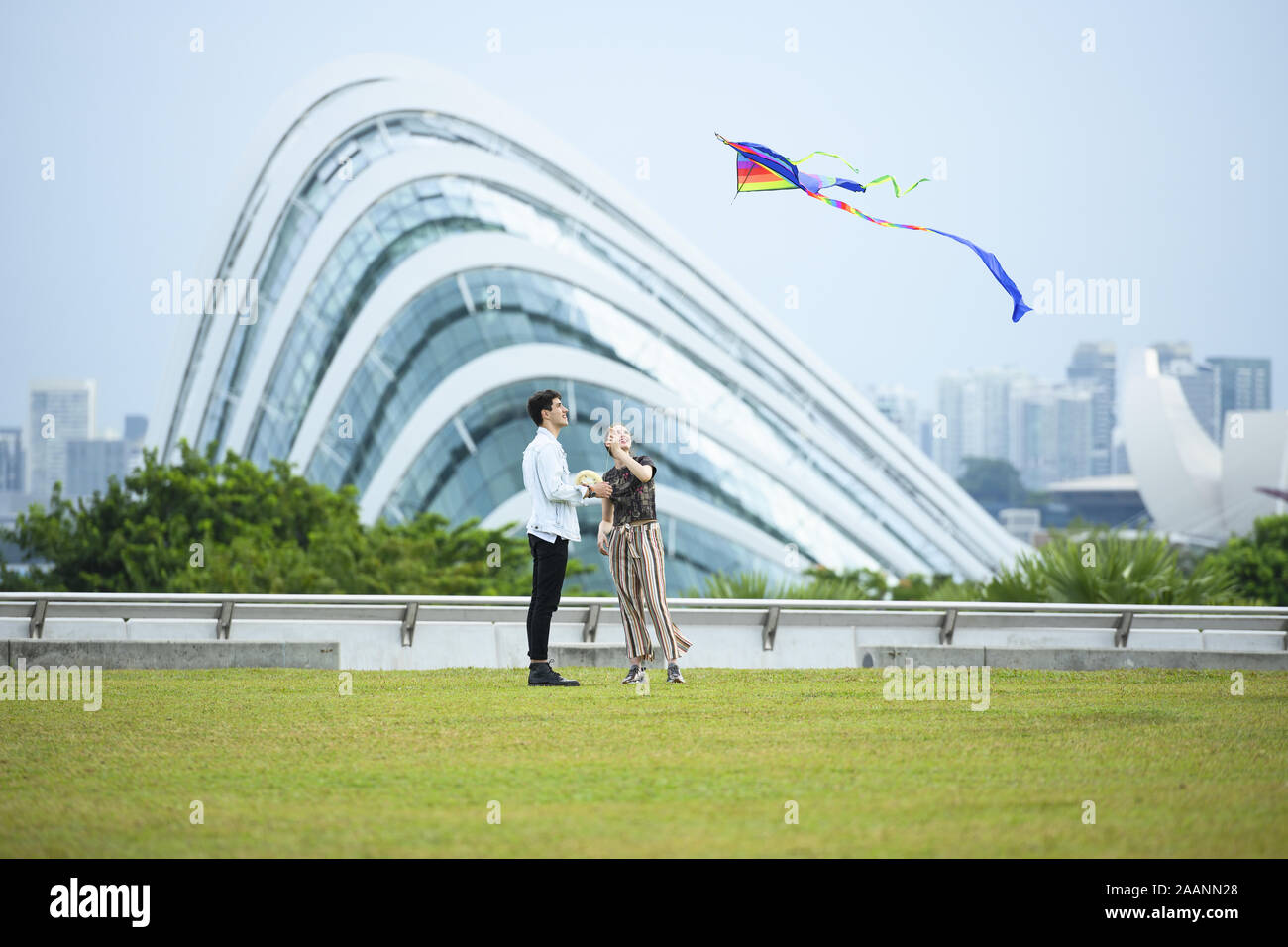 A beautiful happy couple are playing with kite in a public park in ...