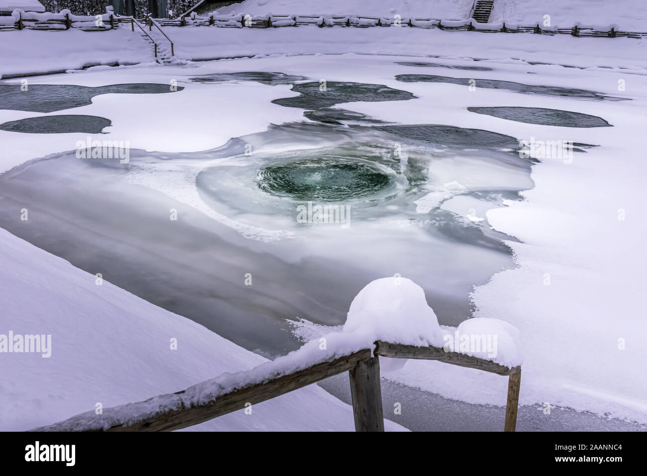 Aerated fish pond in winter. Ice covering the pond is melting, because ...