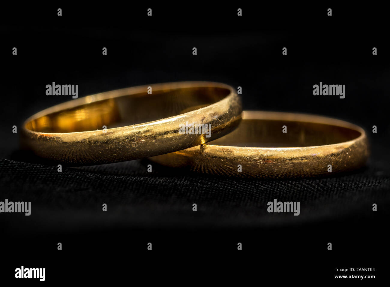 Two worn down golden wedding rings on dark background Stock Photo - Alamy