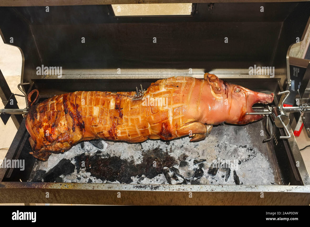 Piglet roasting on a rotating spit Stock Photo - Alamy