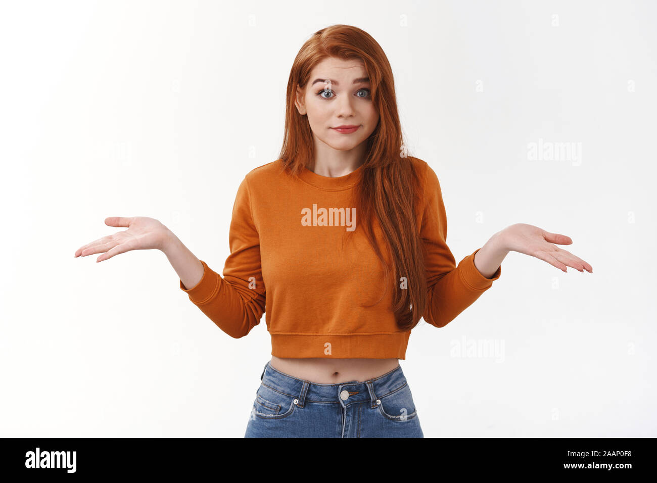 Unaware silly redhead european woman shrugging spread hands sideways ...