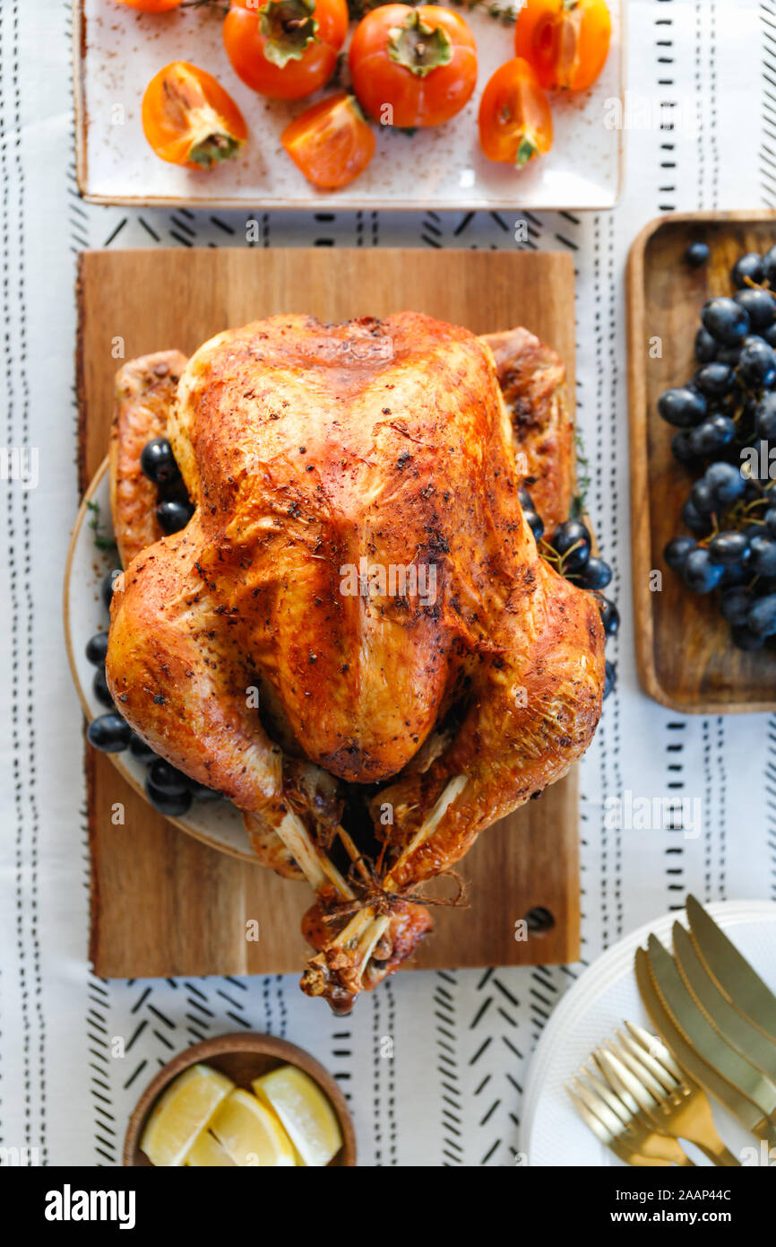 Roasted whole turkey on a table with persimmon, blue grape and lemon ...