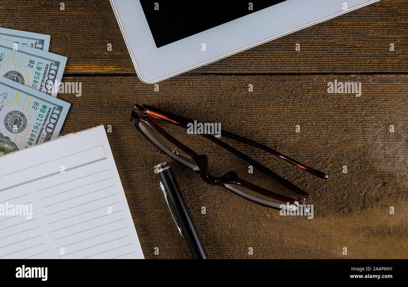 Workspace desk with wooden table US currency money in white table touch ...