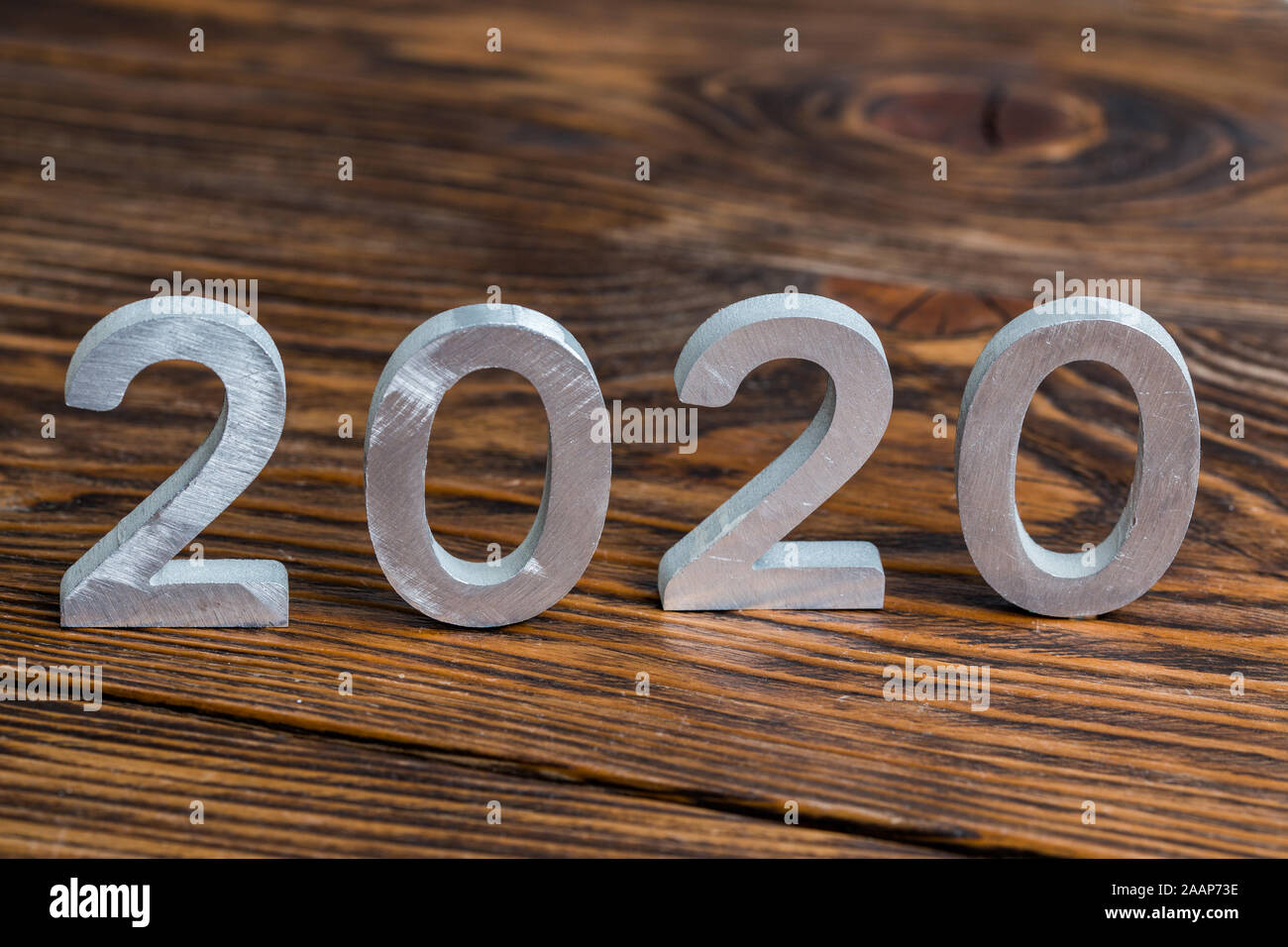 a number 2020 with white metal digits on dark brown wood background ...