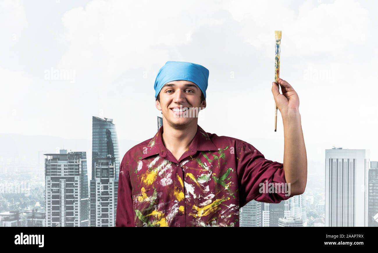 Smiling young painter artist pointing upwards Stock Photo - Alamy