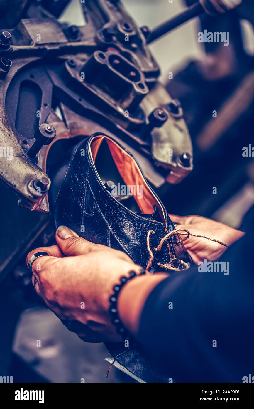Hands of an experienced shoemaker using special machine tool for making ...