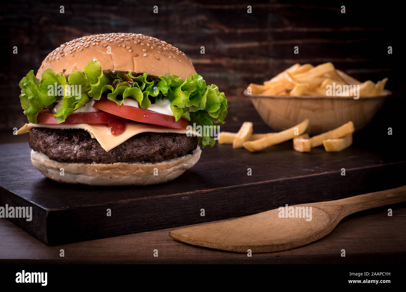 Traditional spicy beef burger with salad and tomato on top of a wooden ...