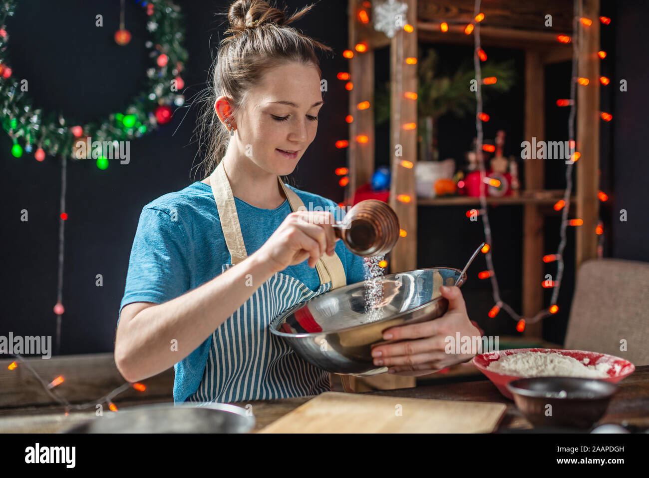 A young woman housewife makes dough for cooking festive gingerbread on ...