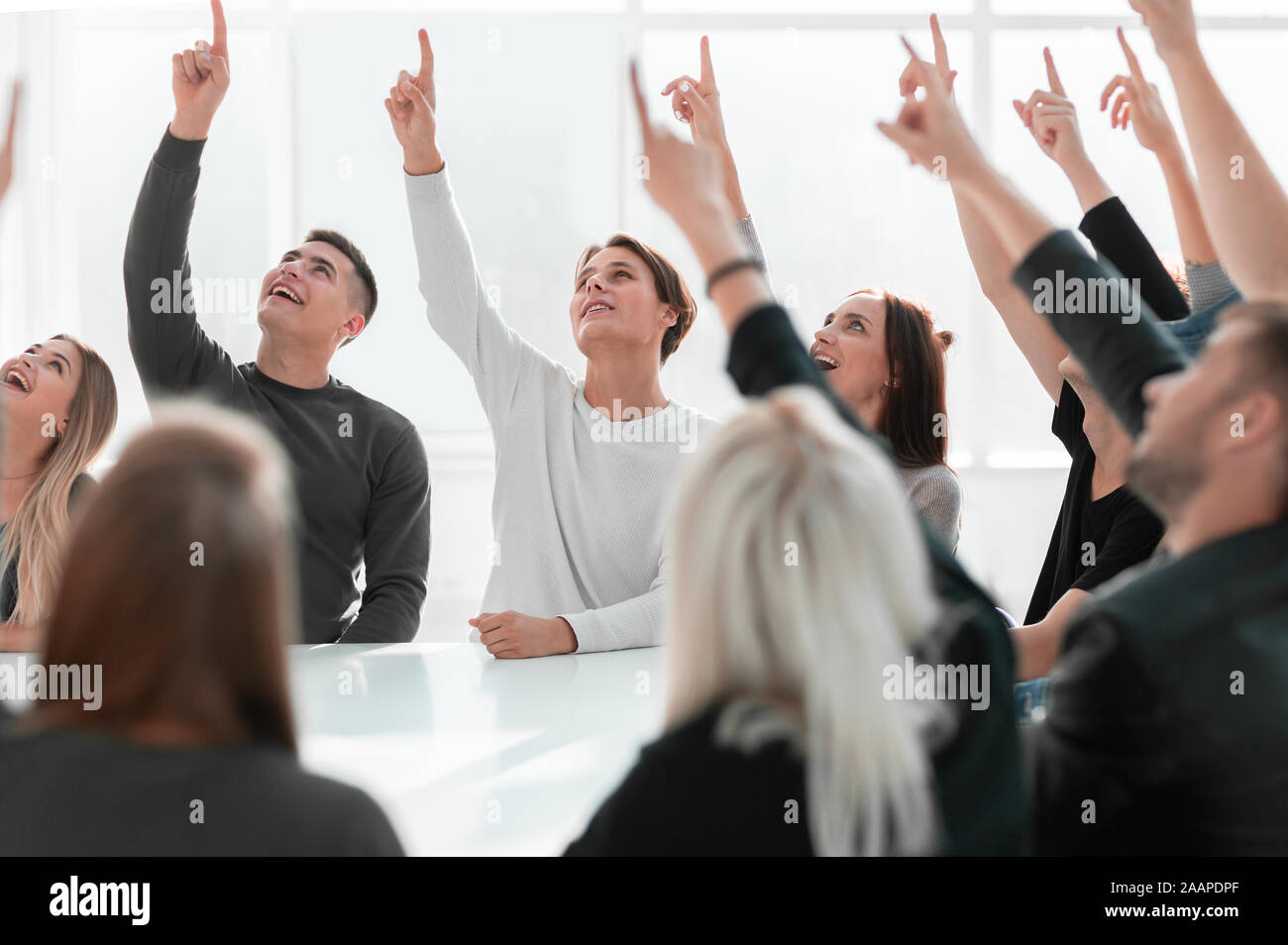 group of young people sitting at a large table and pointing up Stock ...
