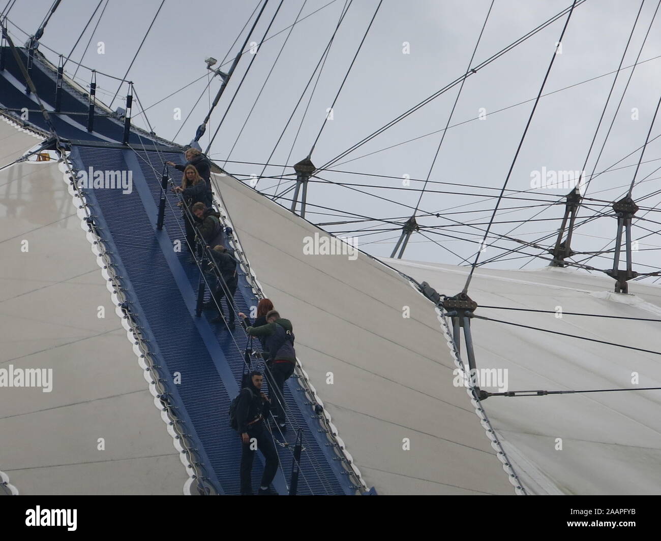 A group of young people are slowly descending the very steep roof of ...