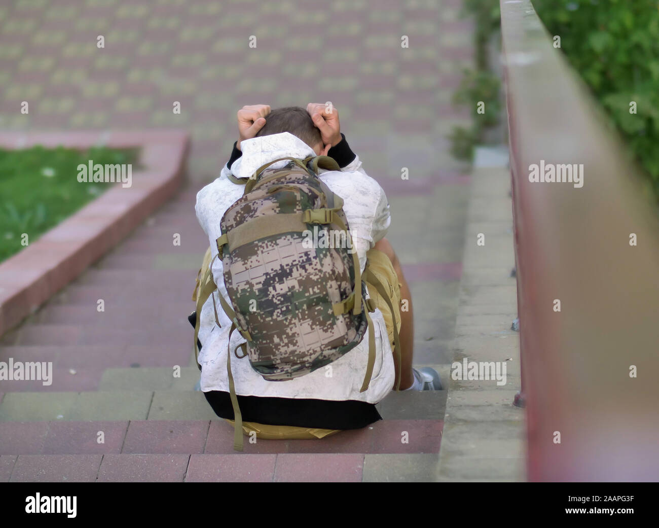 Sad guy sits on the steps of a stone staircase Stock Photo - Alamy