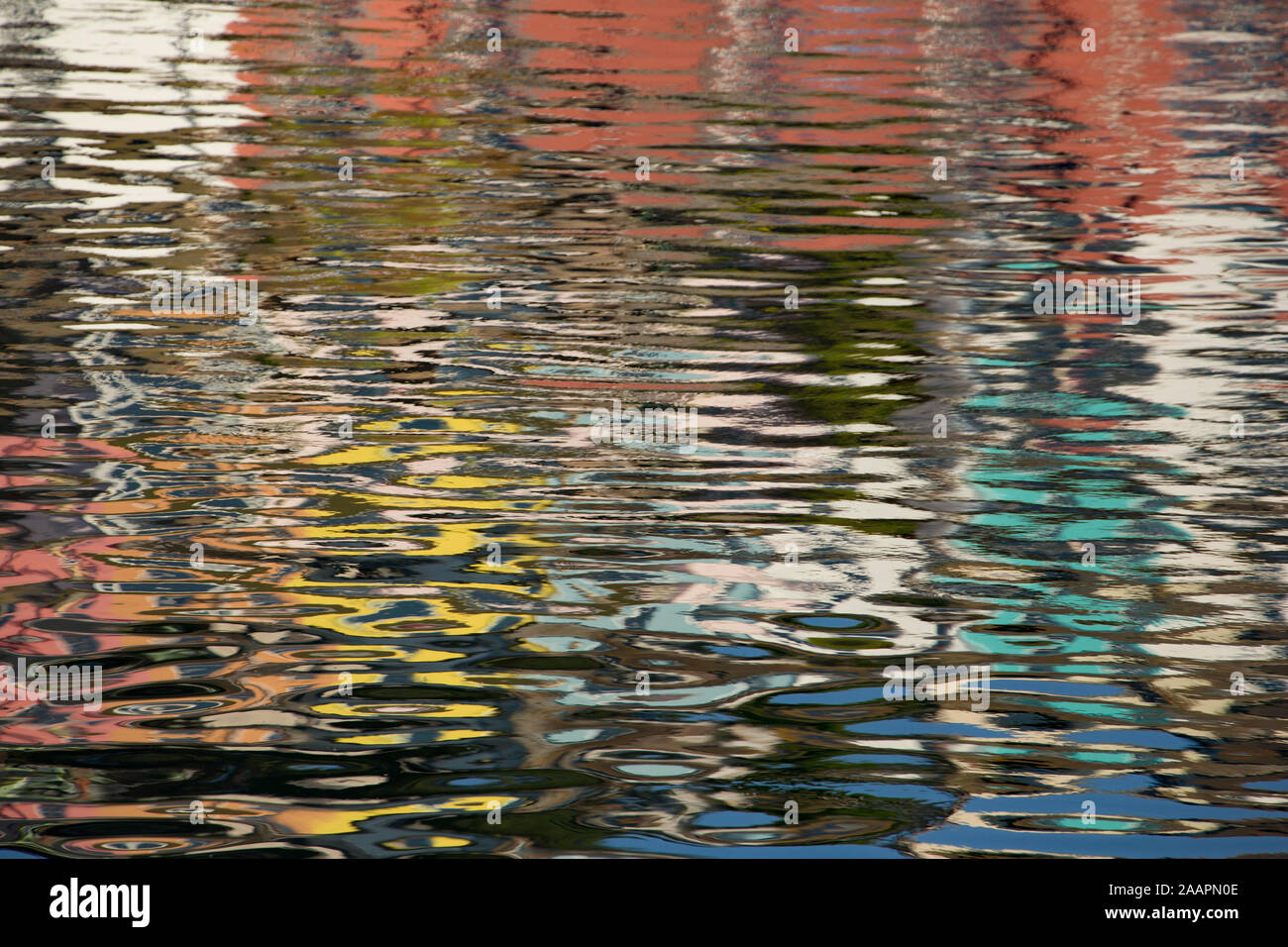 Reflections in the water of colourful houses on a hillside overlooking ...