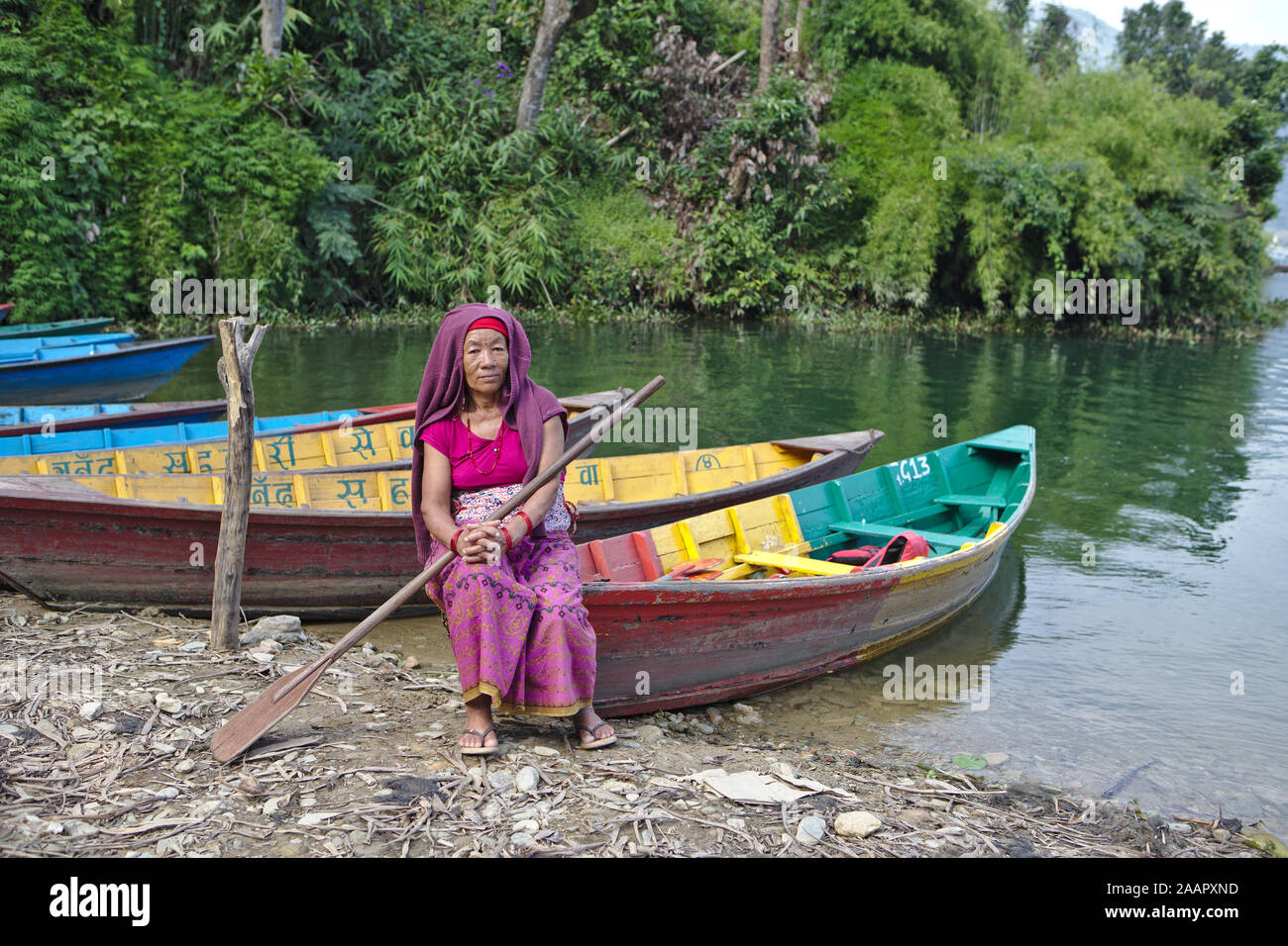 female nepalese boat driver wearing pink sitting on boat by the ...