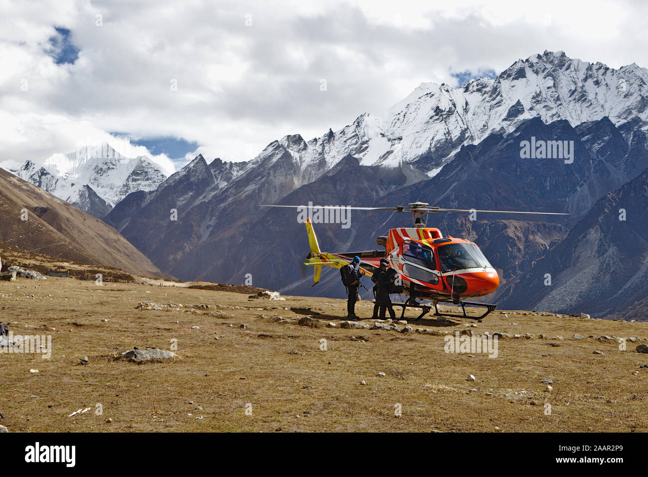 red and yellow helicopter coming in to land in Kyanjin Gompa Stock ...