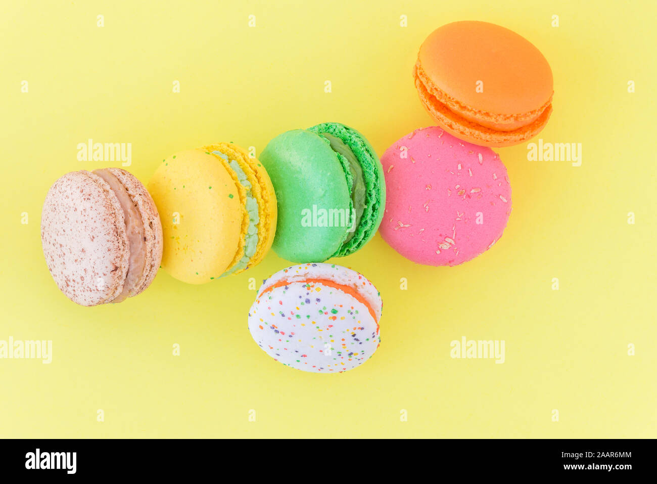 Sweet colorful French macaroon biscuits on pastel yellow background ...