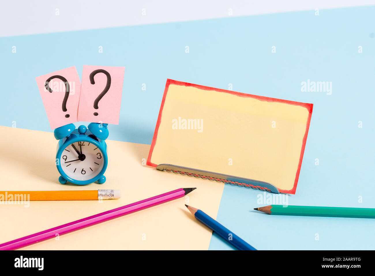 Mini size alarm clock beside stationary placed tilted on pastel ...