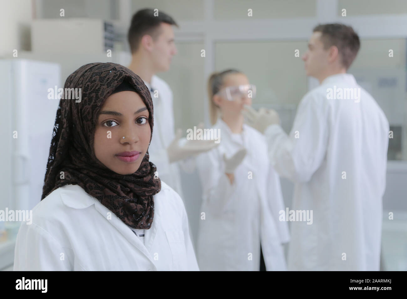 Group of young scientists doing experiments in laboratory with afro ...