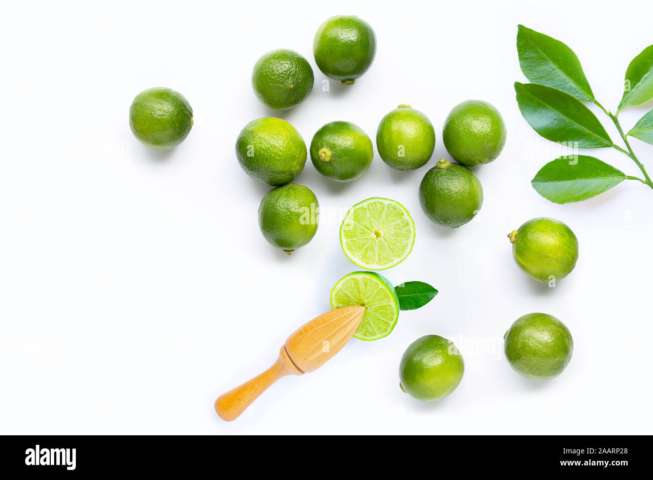 Fresh limes and leaves with wooden juicer on white background. Copy ...