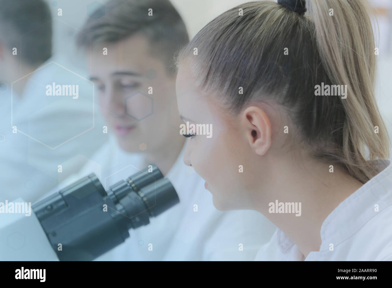 Two young male and female students scientists doing experiments in ...