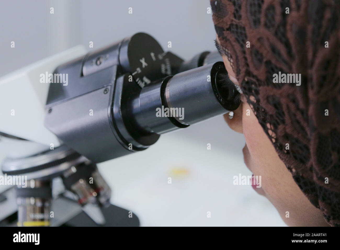 Young african muslim female scientist looking through a microscope in a ...