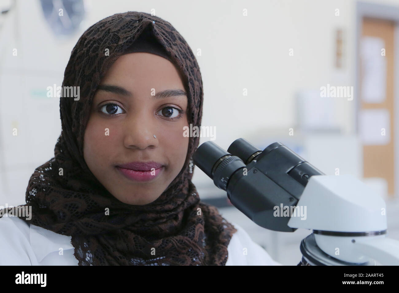 Young african muslim female scientist looking through a microscope in a ...