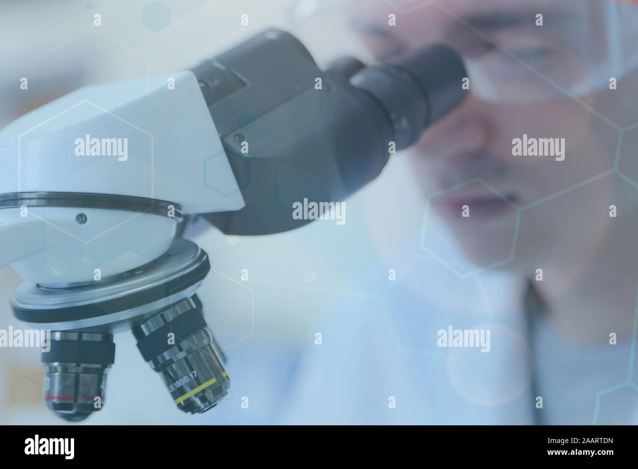 Young male scientist looking through a microscope in a laboratory doing ...