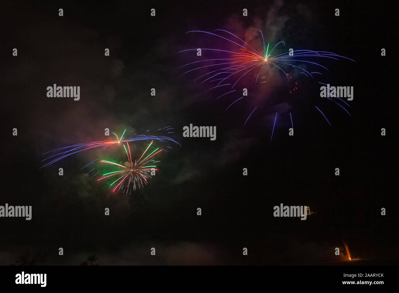 Multi colored fireworks making wake effect over trees silhouette Stock ...