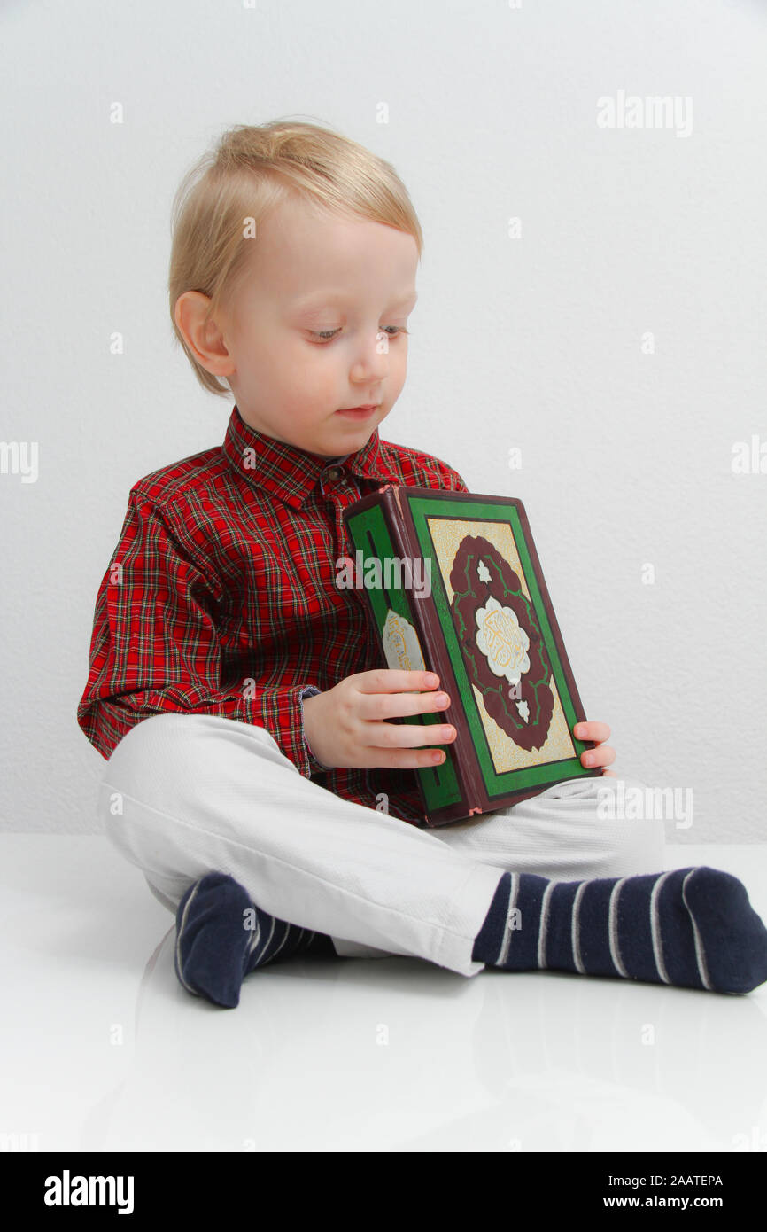Little muslim European boy with islamic holy book Quran or Kuran Stock ...