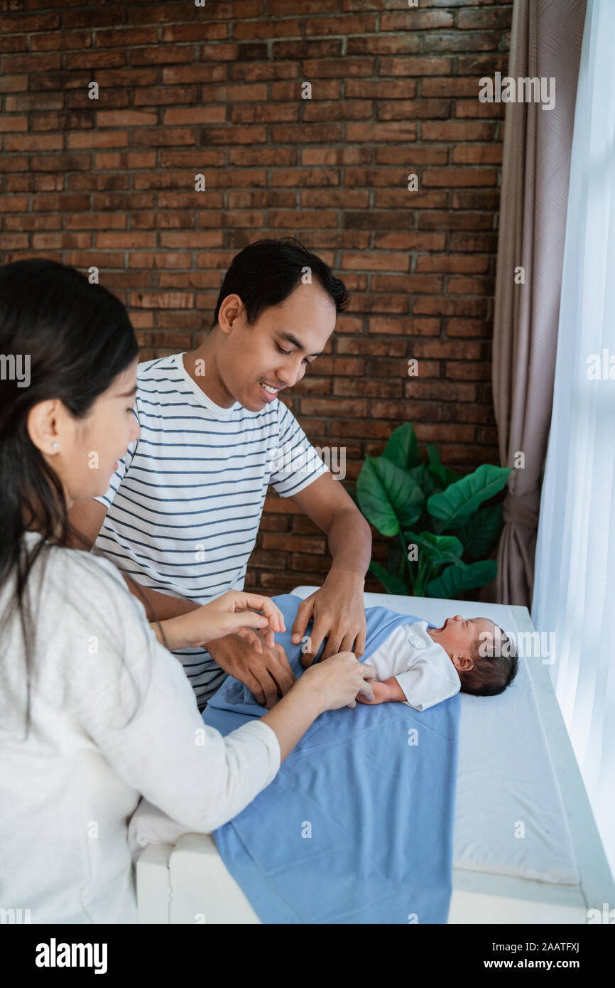 father and mother changing the nappy of her baby lying Stock Photo - Alamy