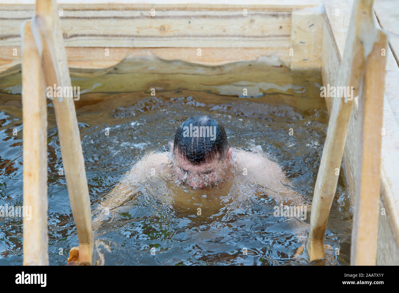 Man bathes into cold water of ice-hole on Epiphany day. Traditional ice ...