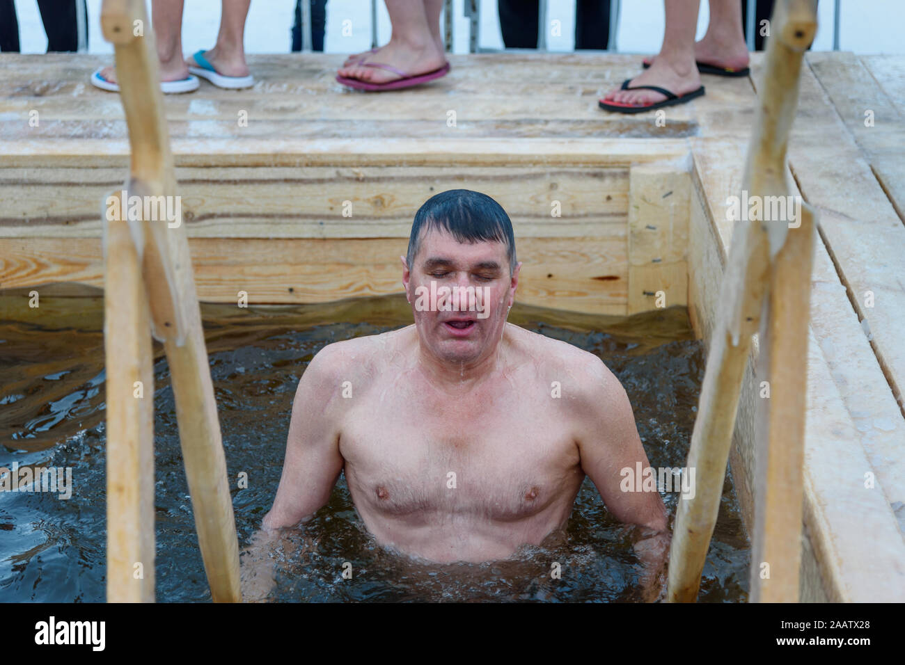 Man bathes into cold water of ice-hole on Epiphany day. Traditional ice ...