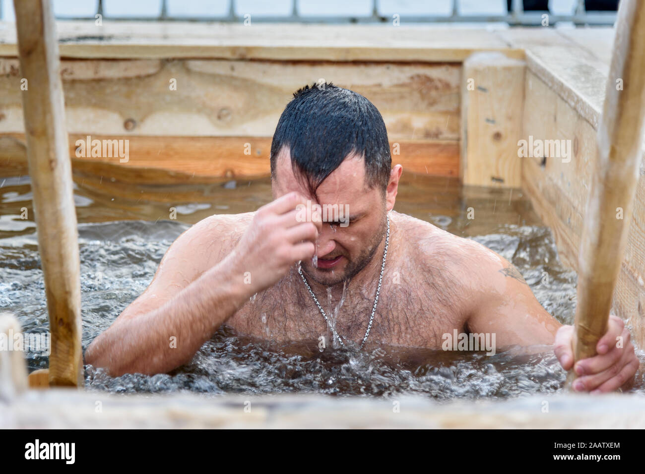 Man bathes into cold water of ice-hole on Epiphany day. Traditional ice ...