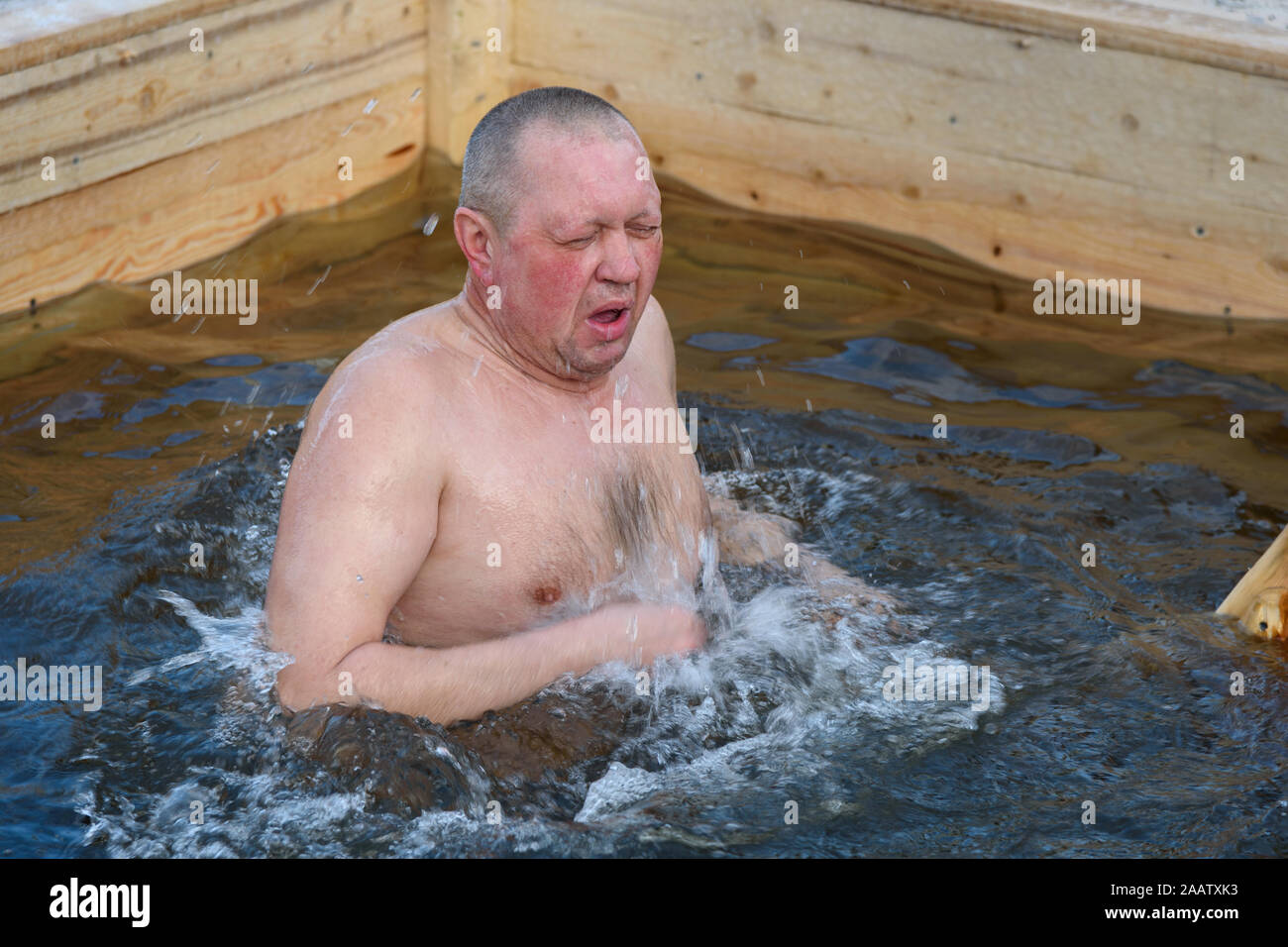Man bathes into cold water of ice-hole on Epiphany day. Traditional ice ...