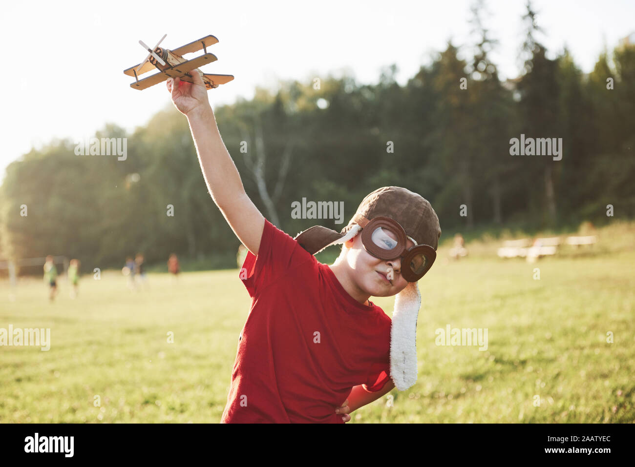 Happy kid in pilot helmet playing with a wooden toy airplane and ...