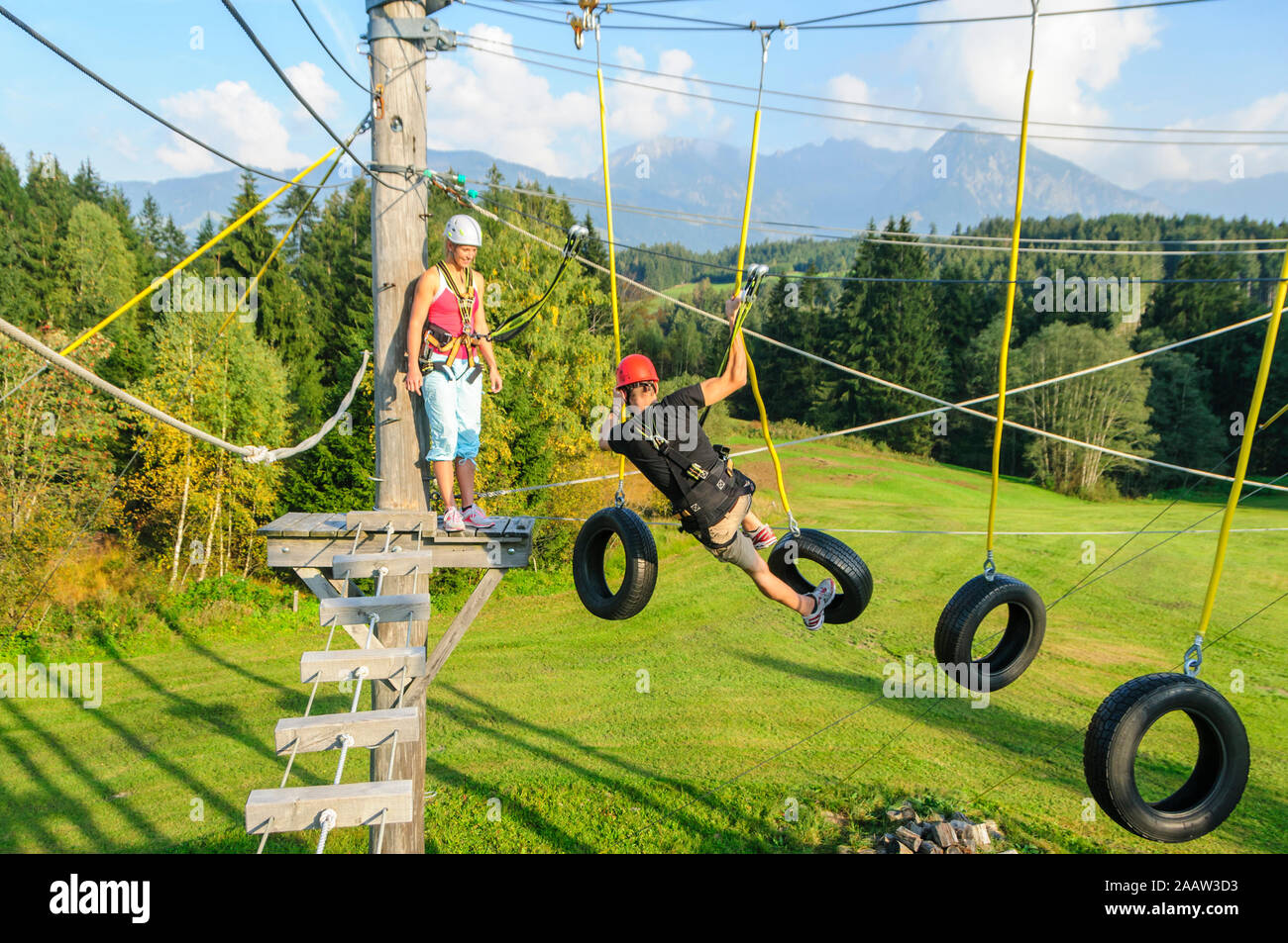 Young people doing exercises in high rope course at a sunny day Stock ...