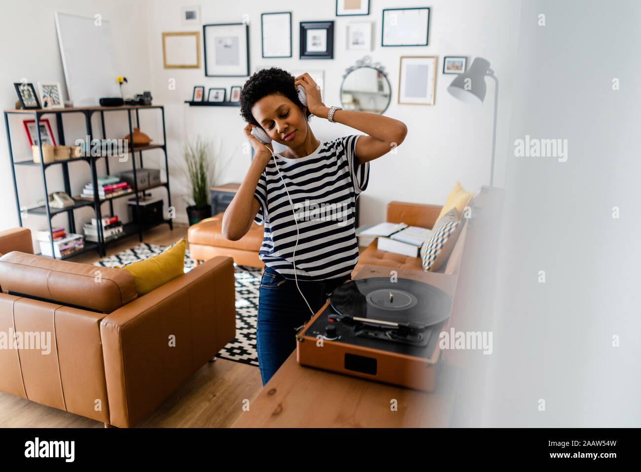 Happy young woman listening to music with headphones and record player ...