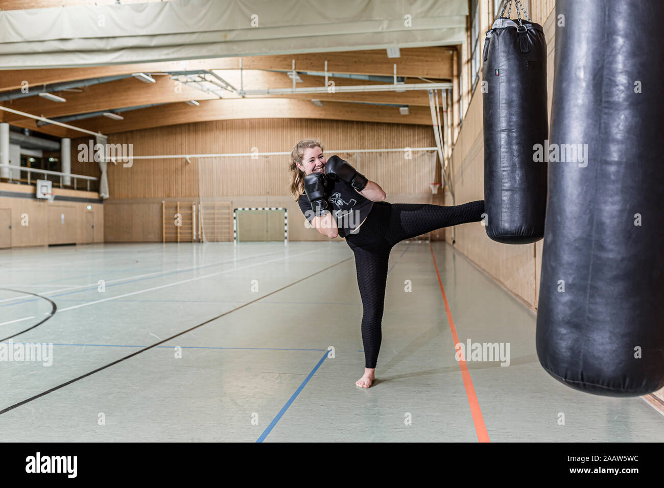 Female kickboxer practising at punchbag in sports hall Stock Photo - Alamy