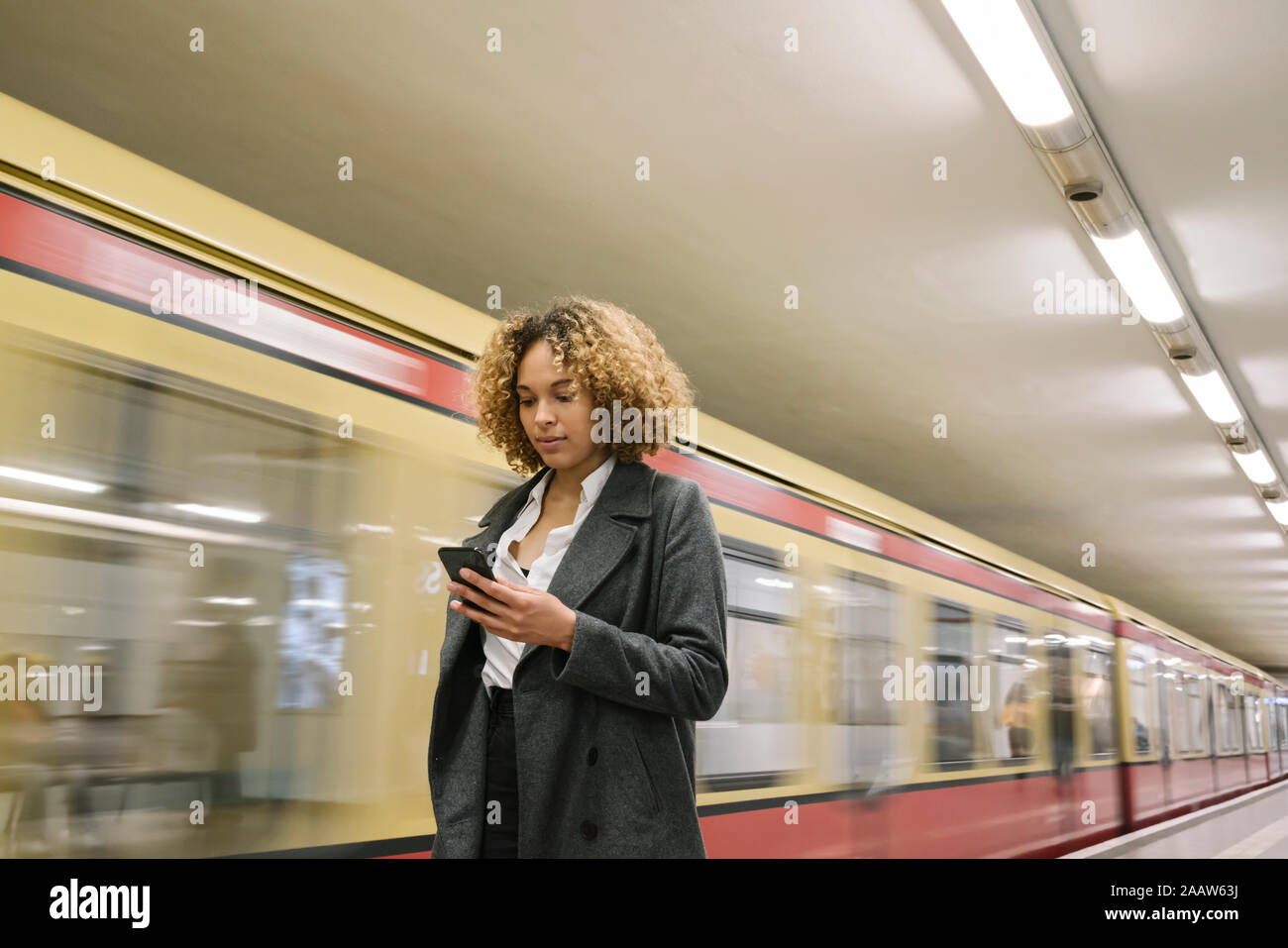 Woman using cell phone in the subway hi-res stock photography and ...