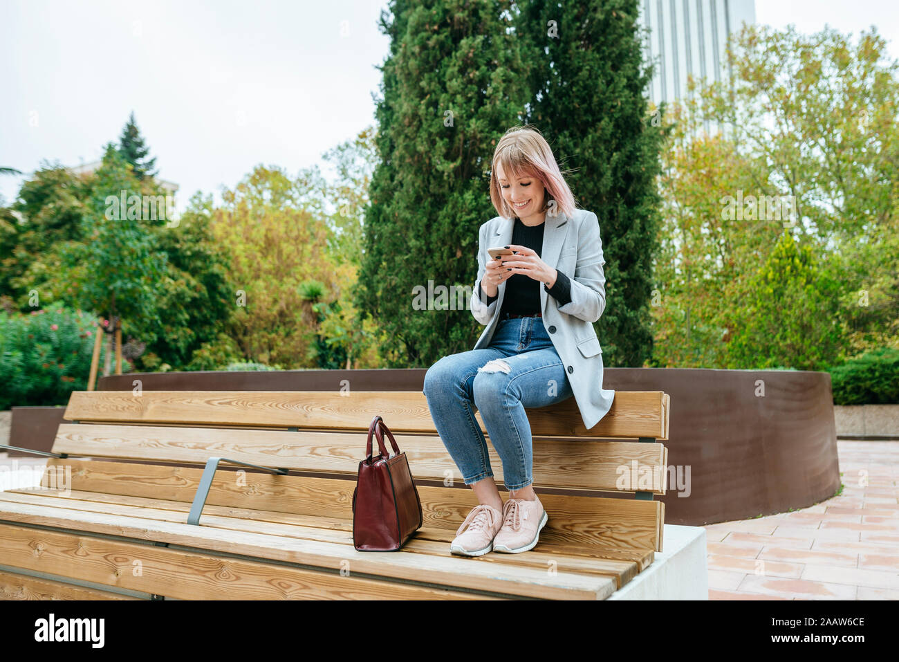 Sitting on park bench with cell phone hi-res stock photography and ...