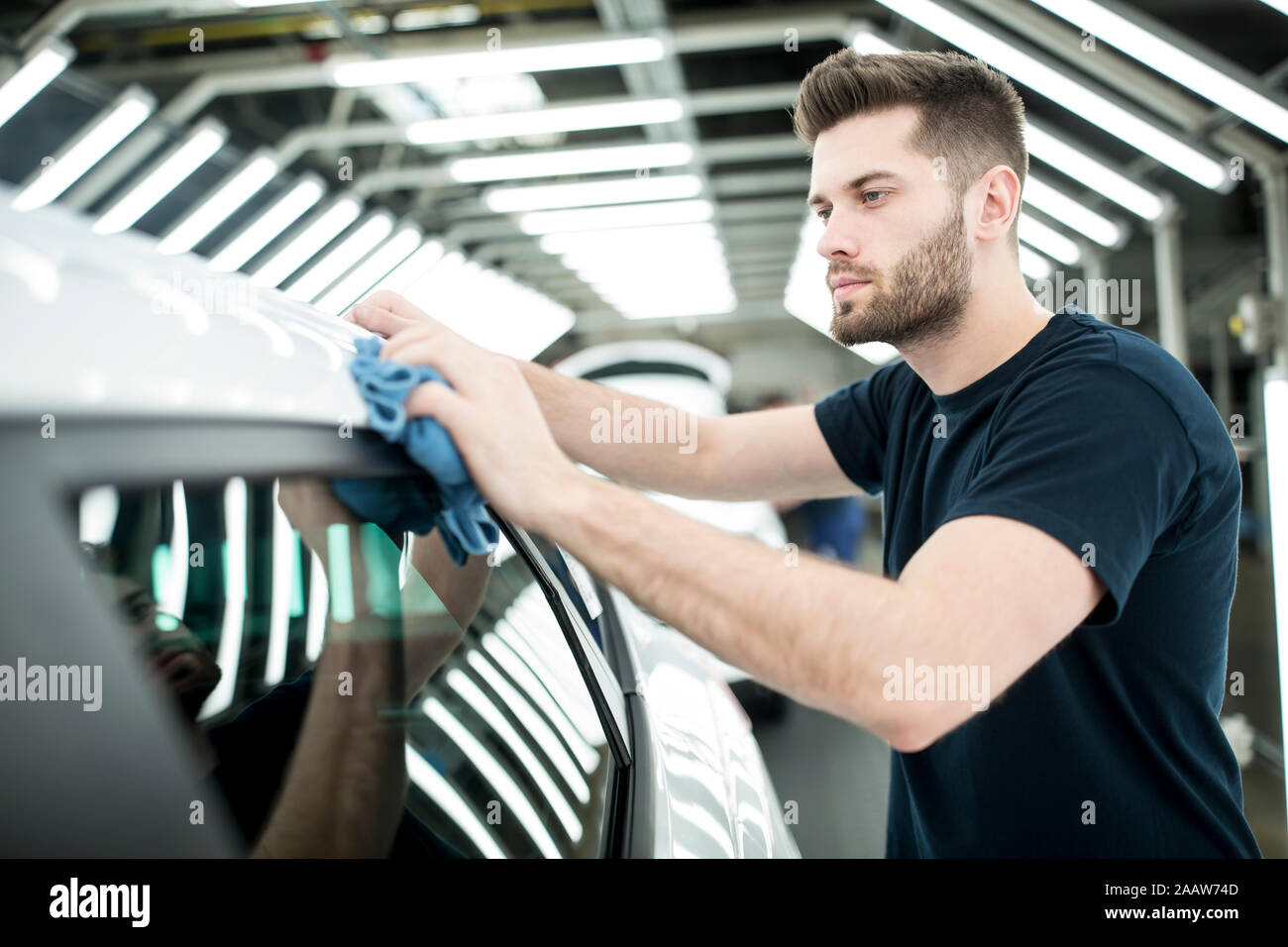 Man working in modern car factory wiping finished car Stock Photo - Alamy