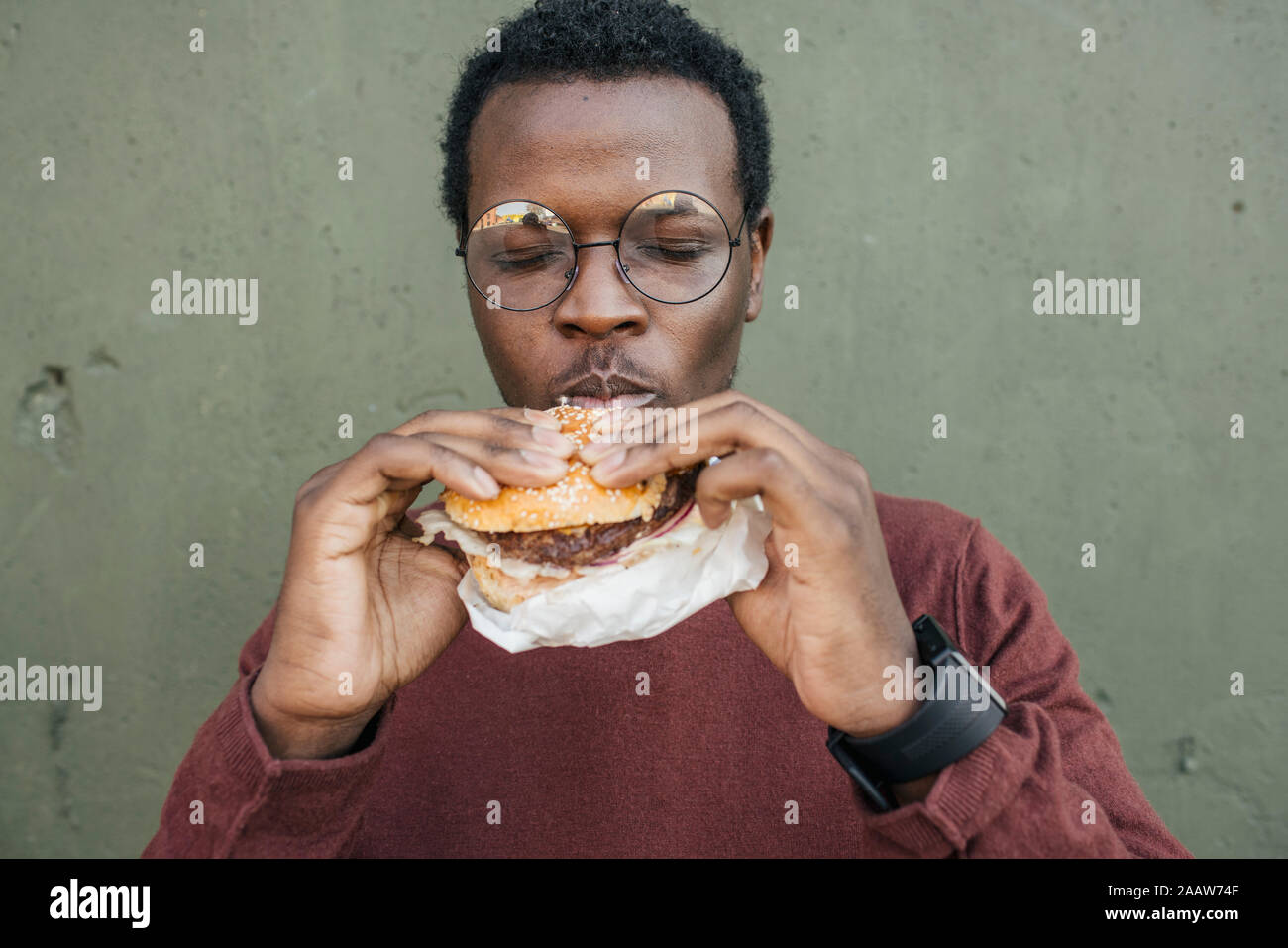 Young man eating cheeseburger, with eyes closed Stock Photo - Alamy