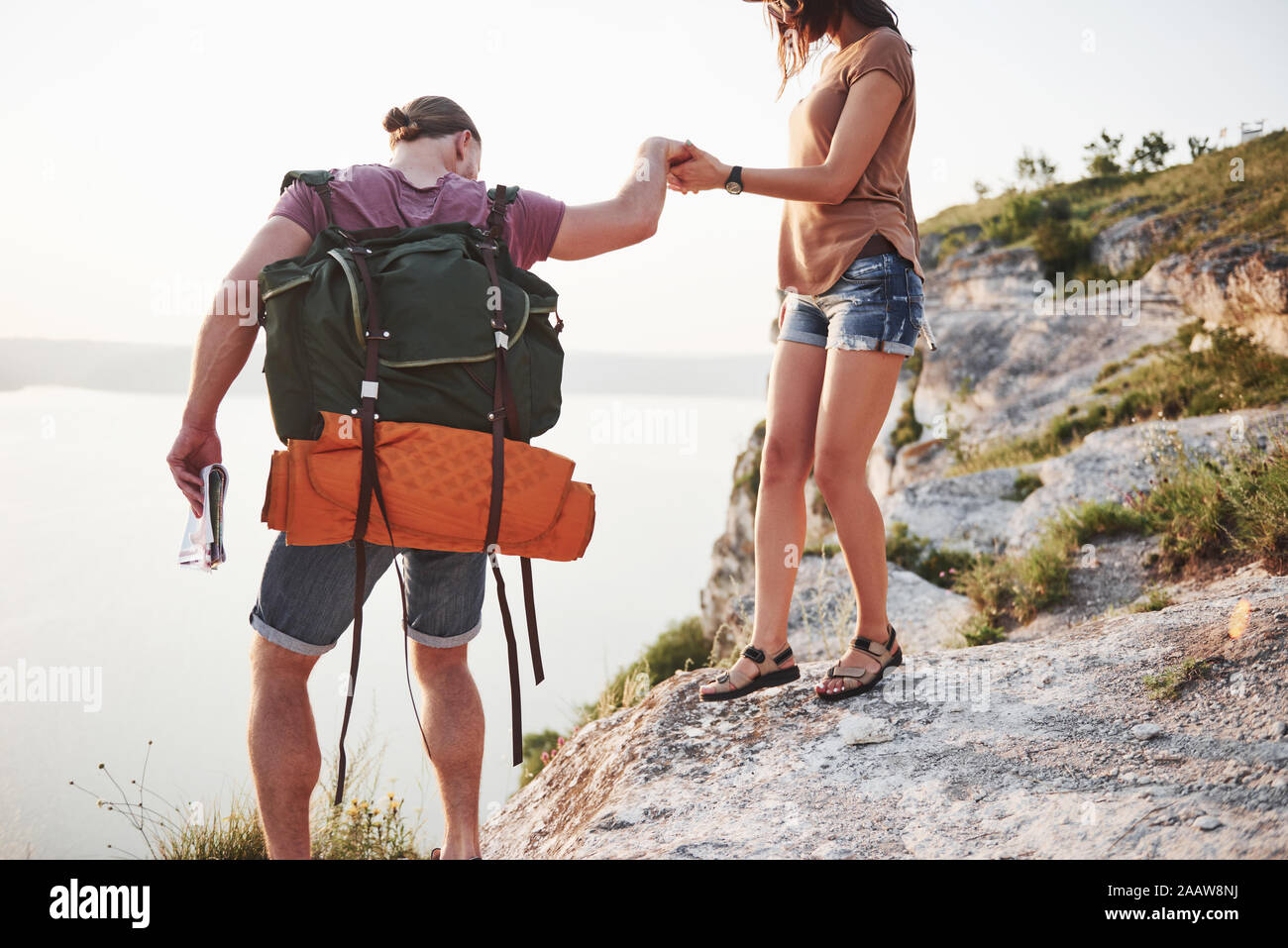 Two tourist male and woman with backpacks climb to the top of the ...