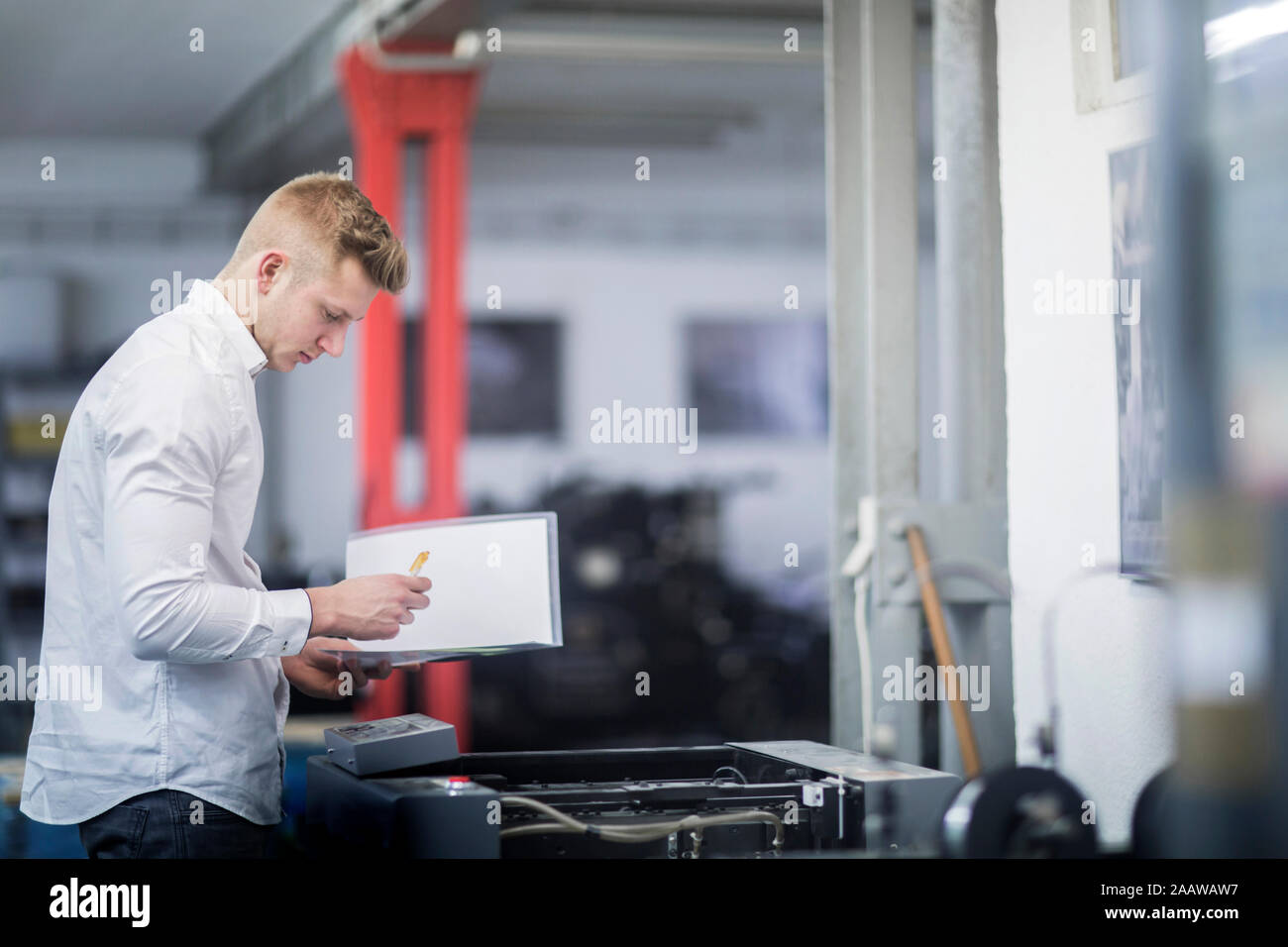 Young man checking printer in a printing company Stock Photo - Alamy