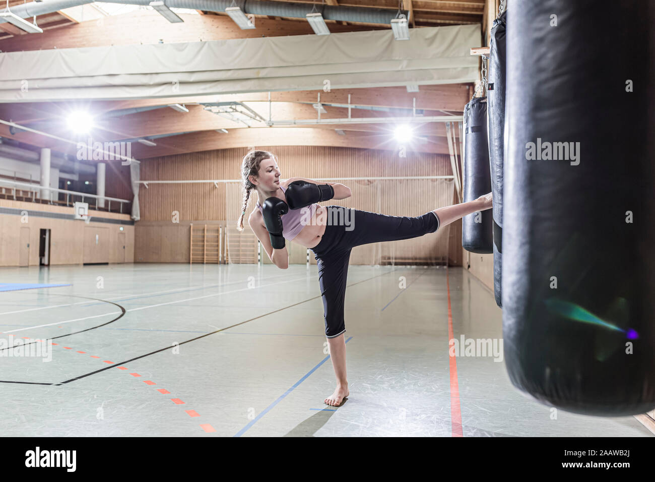 Female kickboxer practising at punchbag in sports hall Stock Photo - Alamy