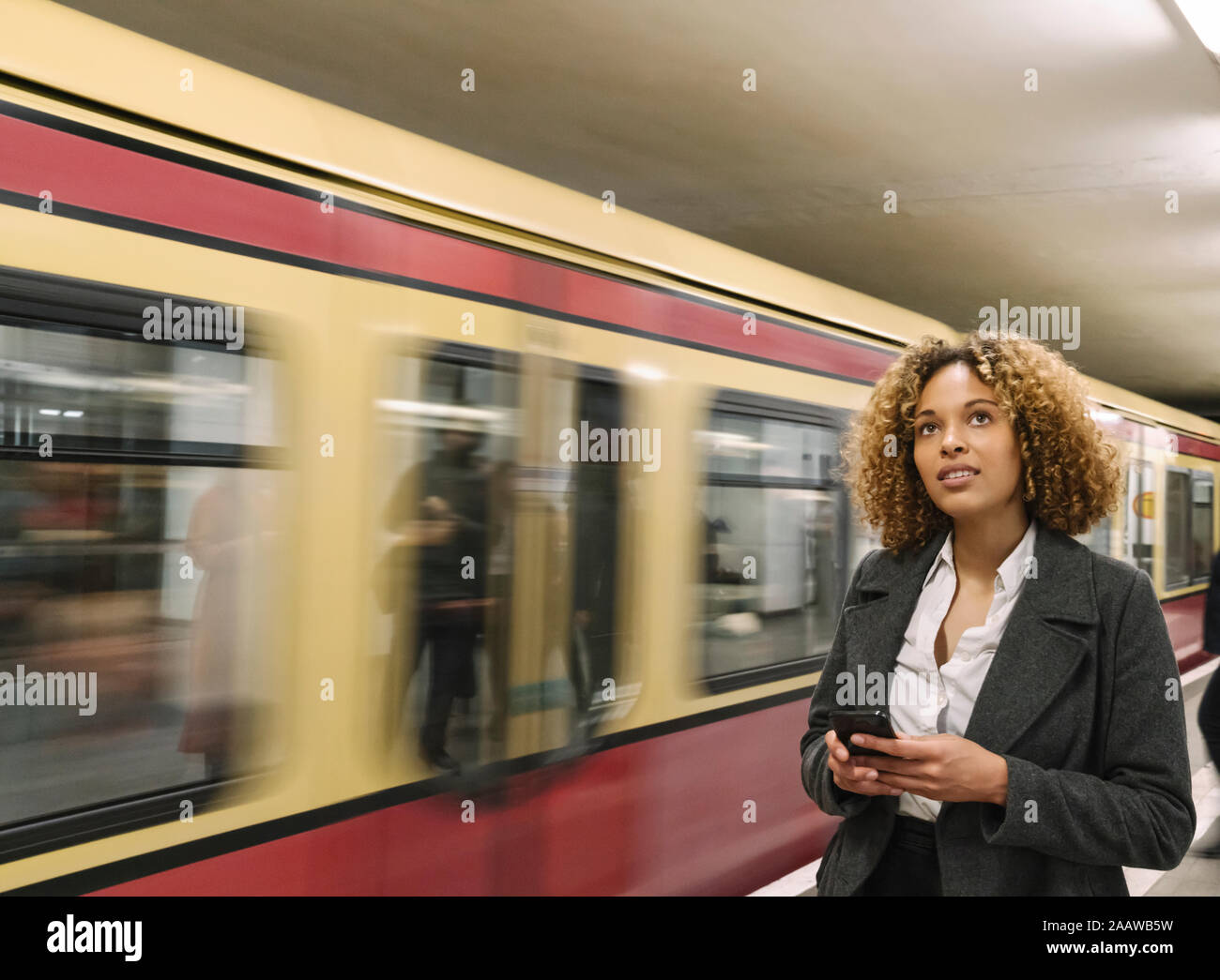 Woman with cell phone in subway station as the train comes in Stock ...
