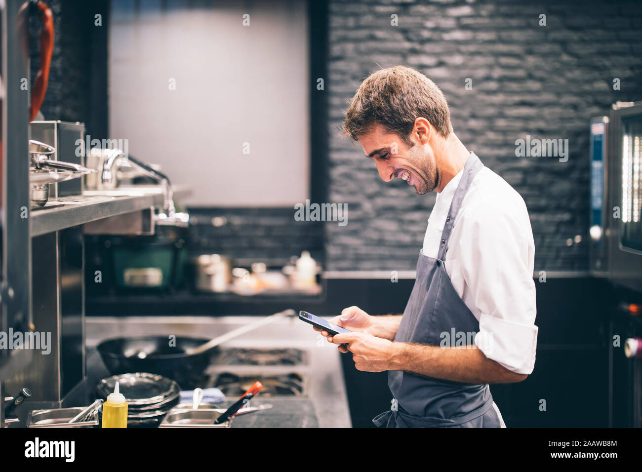 Smiling cook using smartphone in the kitchen of a restaurant Stock ...