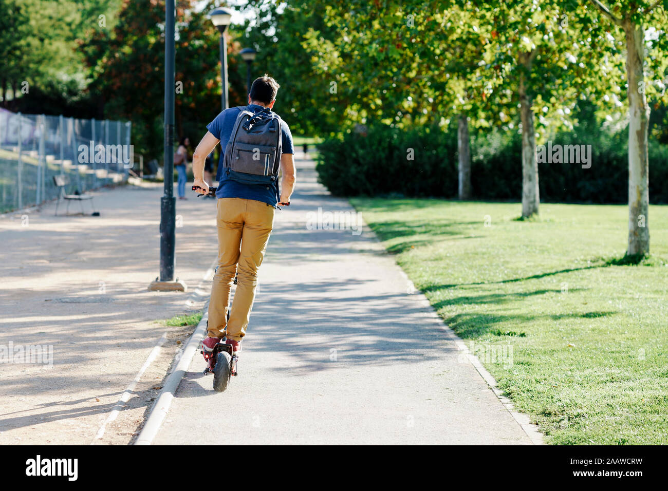 Back view of man with backpack riding electric scooter Stock Photo - Alamy
