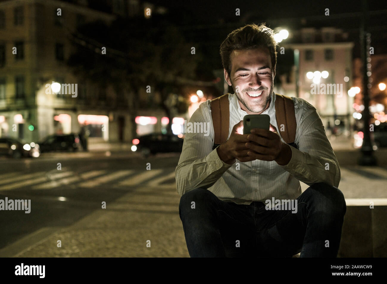 Portrait of happy young man using cell phone in the city by night ...